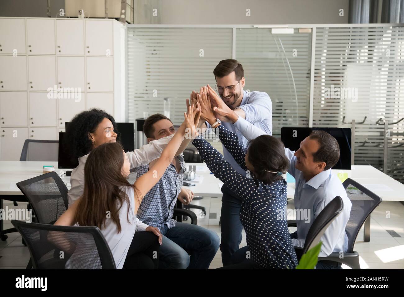 Excited diverse employees give high five motivated for shared goal ...