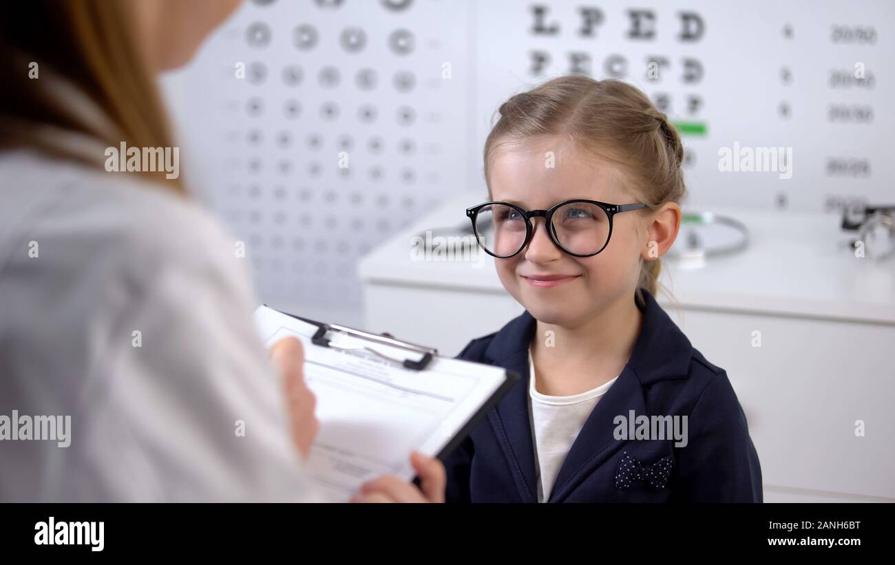 Cute smiling girl waiting eyeglasses prescription from optician ...