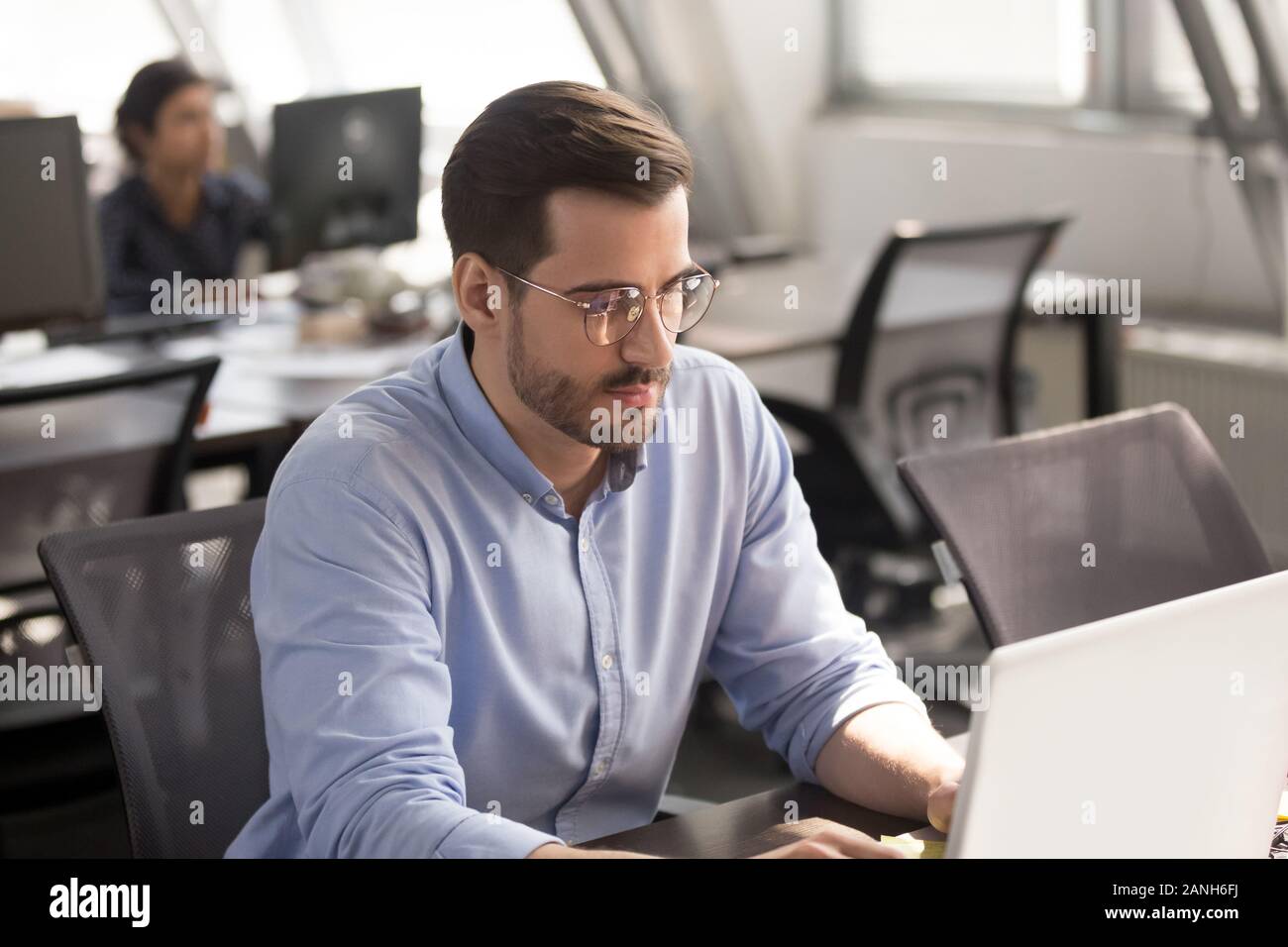 Focused male employee in glasses work on laptop browsing internet in ...