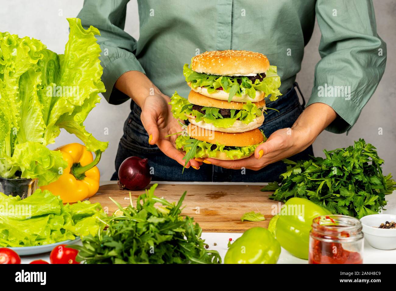 Woman holds a big burger in her hands on the kitchen Stock Photo - Alamy