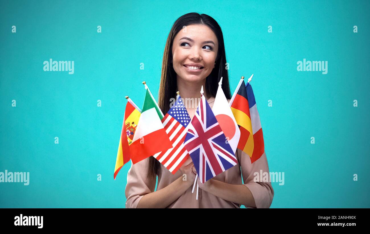 Smiling asian woman holding different countries flags, international ...