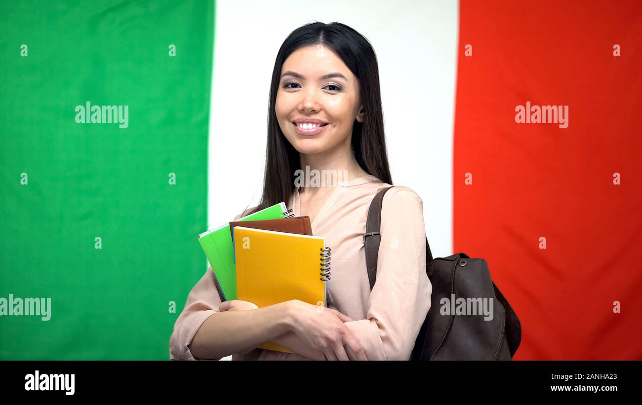 Female student standing with copybooks against Italian flag on ...