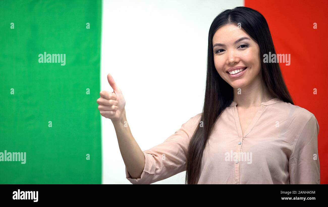 Happy female showing thumbs-up against Italian flag background ...