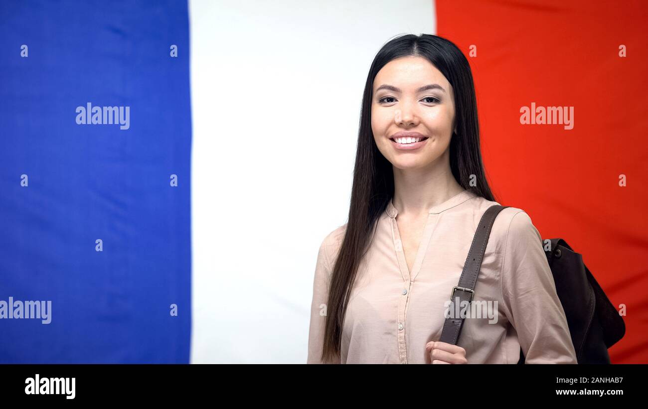 Smiling student with backpack standing against French flag, education ...