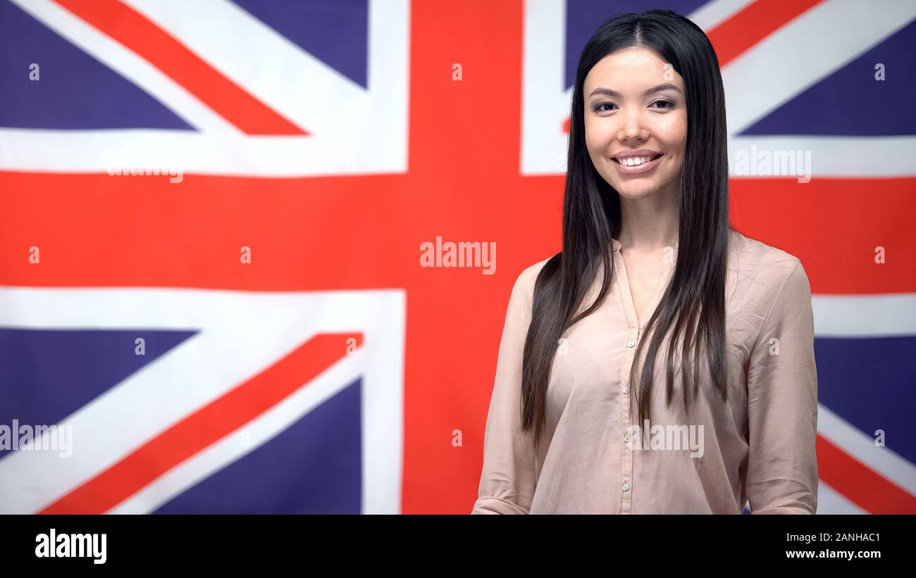 Pretty lady standing against British flag background, international ...