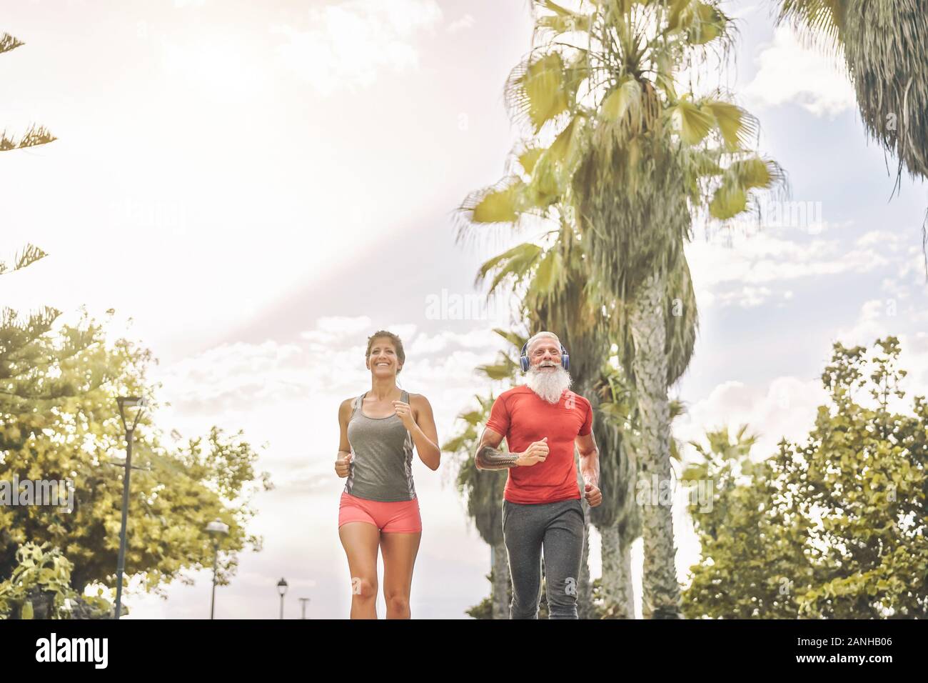 Fit friends jogging together in park outdoor - Sporty mature people ...