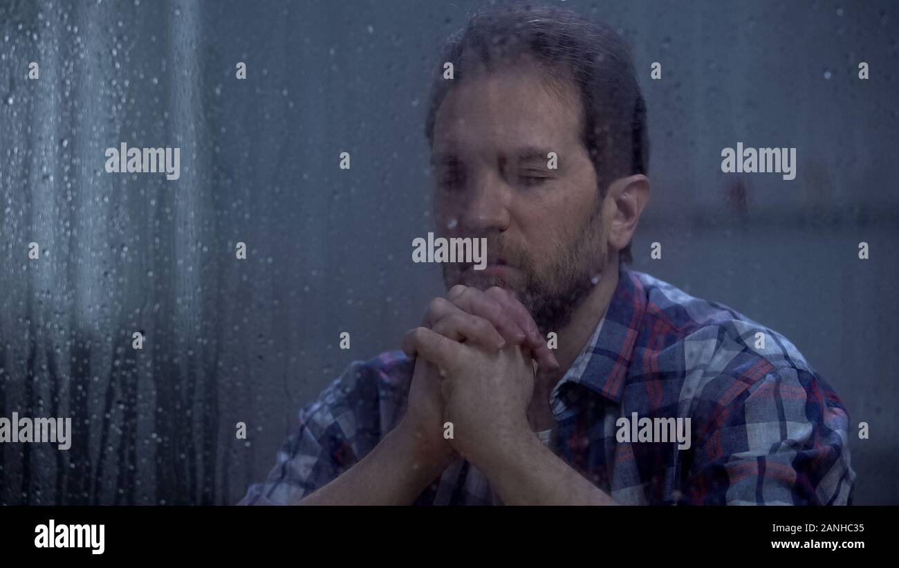 Adult man praying, asking God for mercy and strength, rainy weather ...