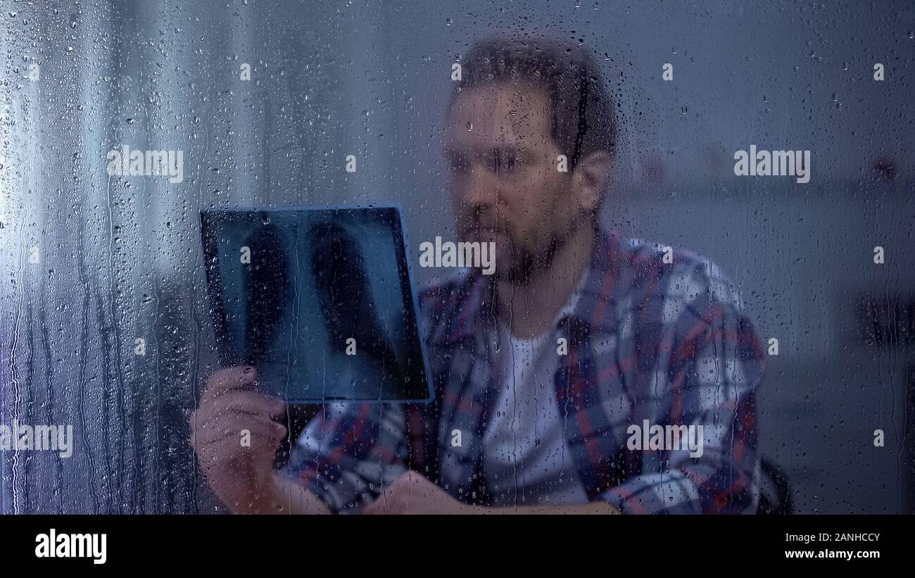 Sad man looking on lungs x-ray, fatal disease, no hope for recovery ...