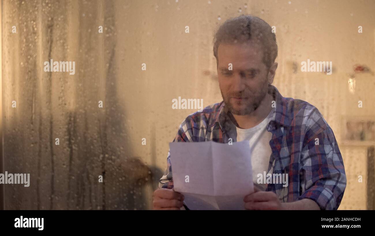 Happy man reading letter from beloved behind rainy window, distance ...