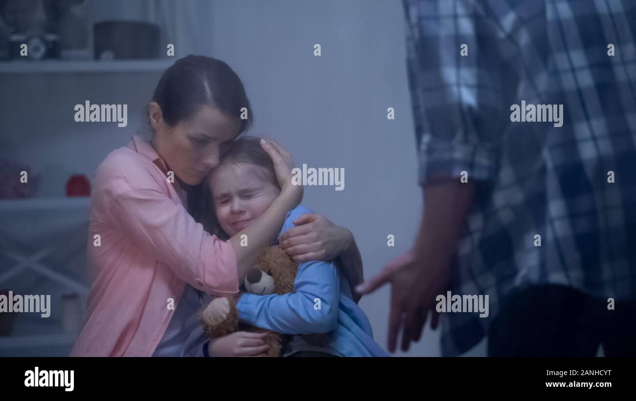 Mother hugging daughter, protecting from angry father, harassment in ...