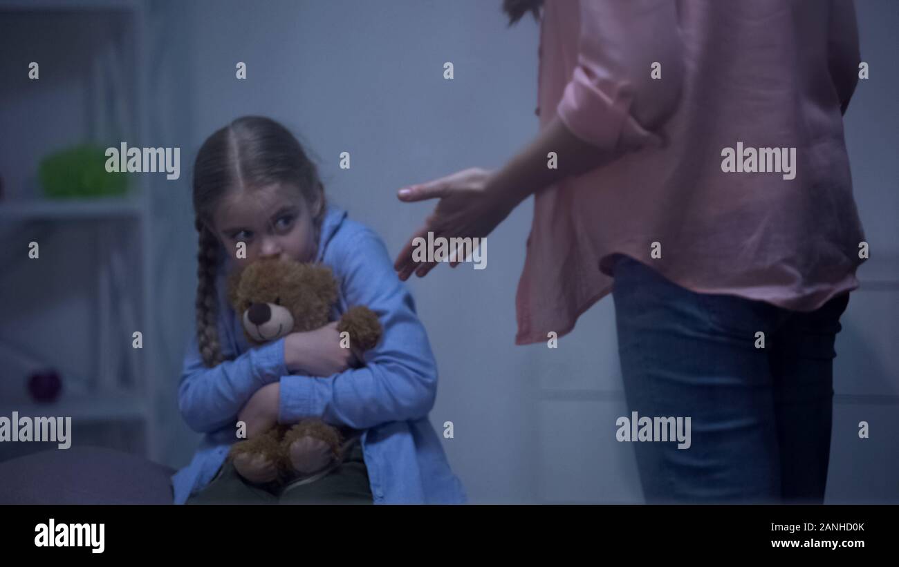 Angry mother screaming on daughter hugging teddy, domestic violence ...