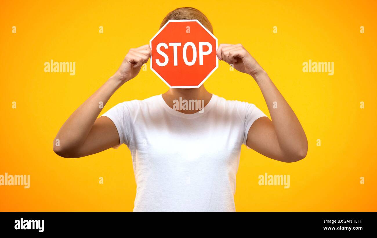 Young woman holding red stop sign front face, negative reaction ...