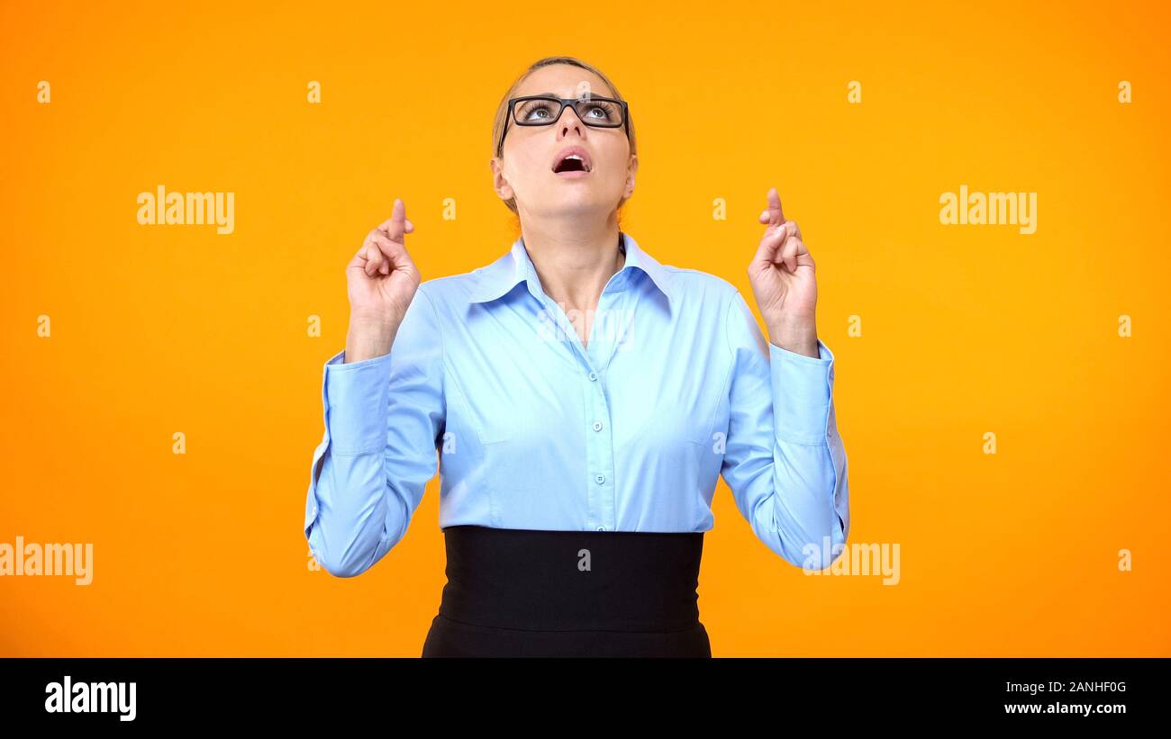 Hopeful business lady crossed fingers looking up, begging for career ...