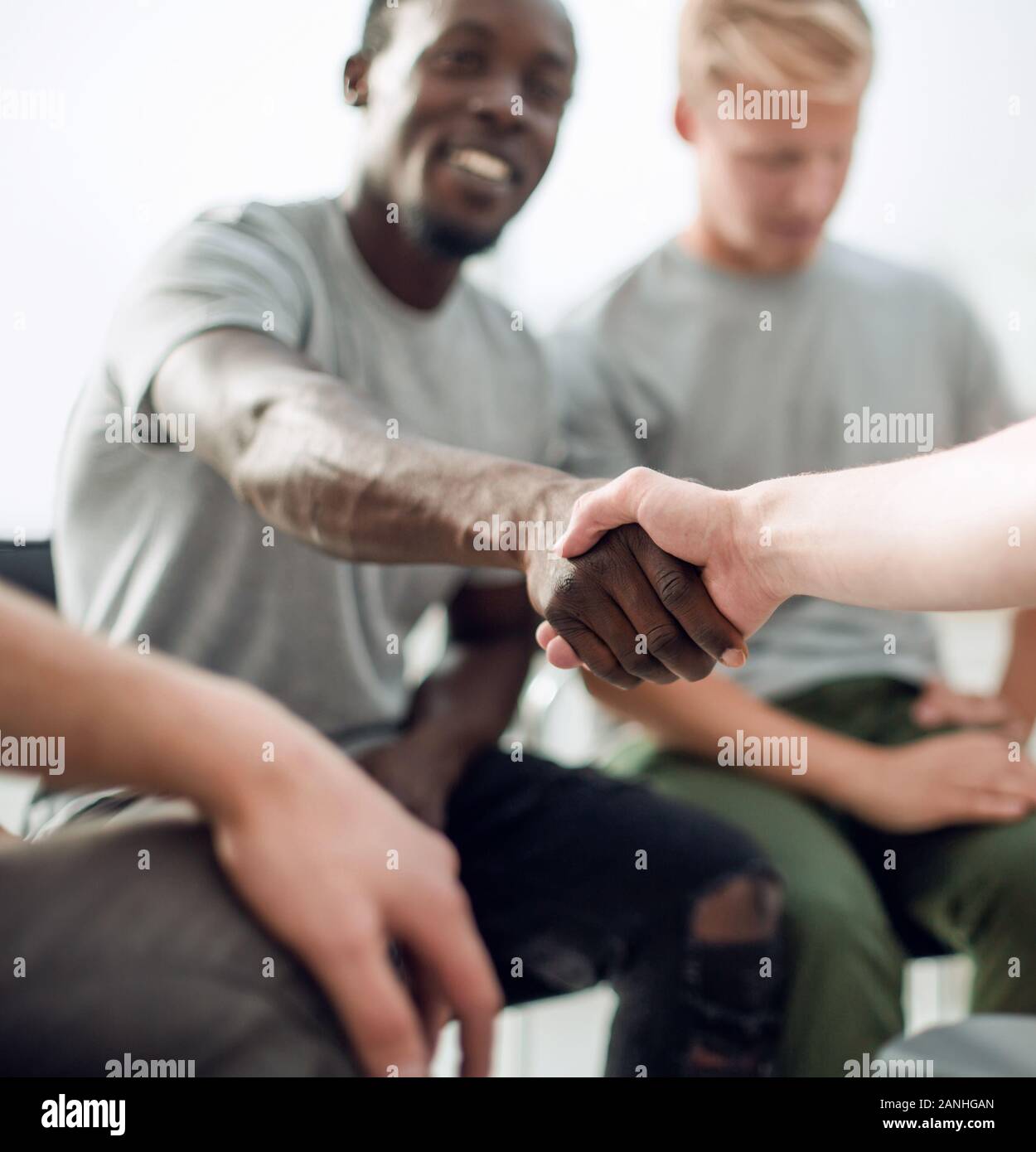 close up. smiling guy shaking hands with his friend Stock Photo - Alamy
