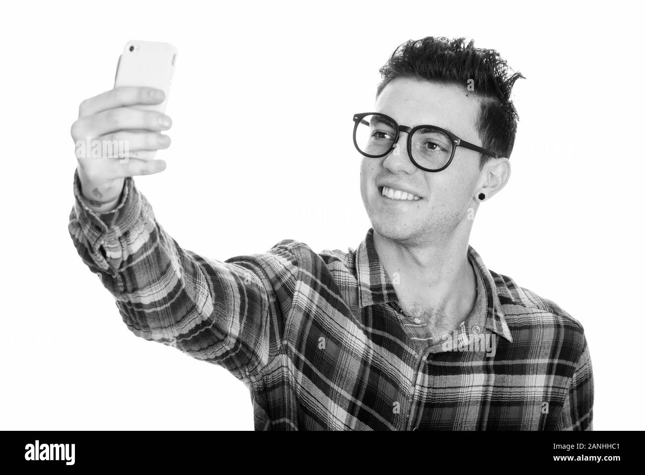 Studio shot of happy young man smiling while taking selfie picture with ...