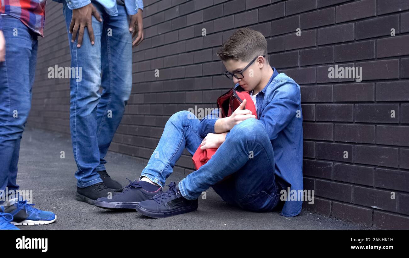 Teen boy leaning against wall, scared of bully students, intimidation ...
