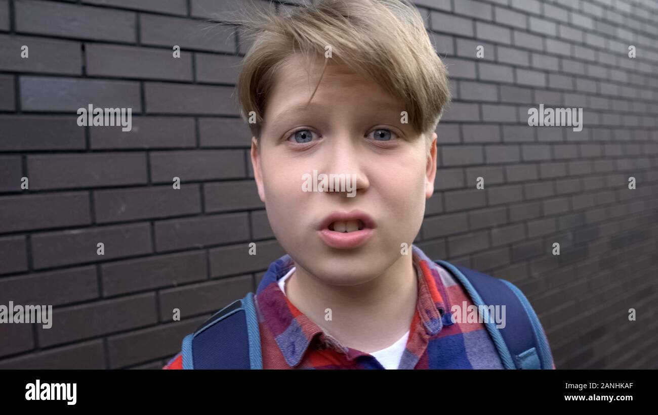 Bully boy teasing into camera, expressing aggression, POV victim of ...