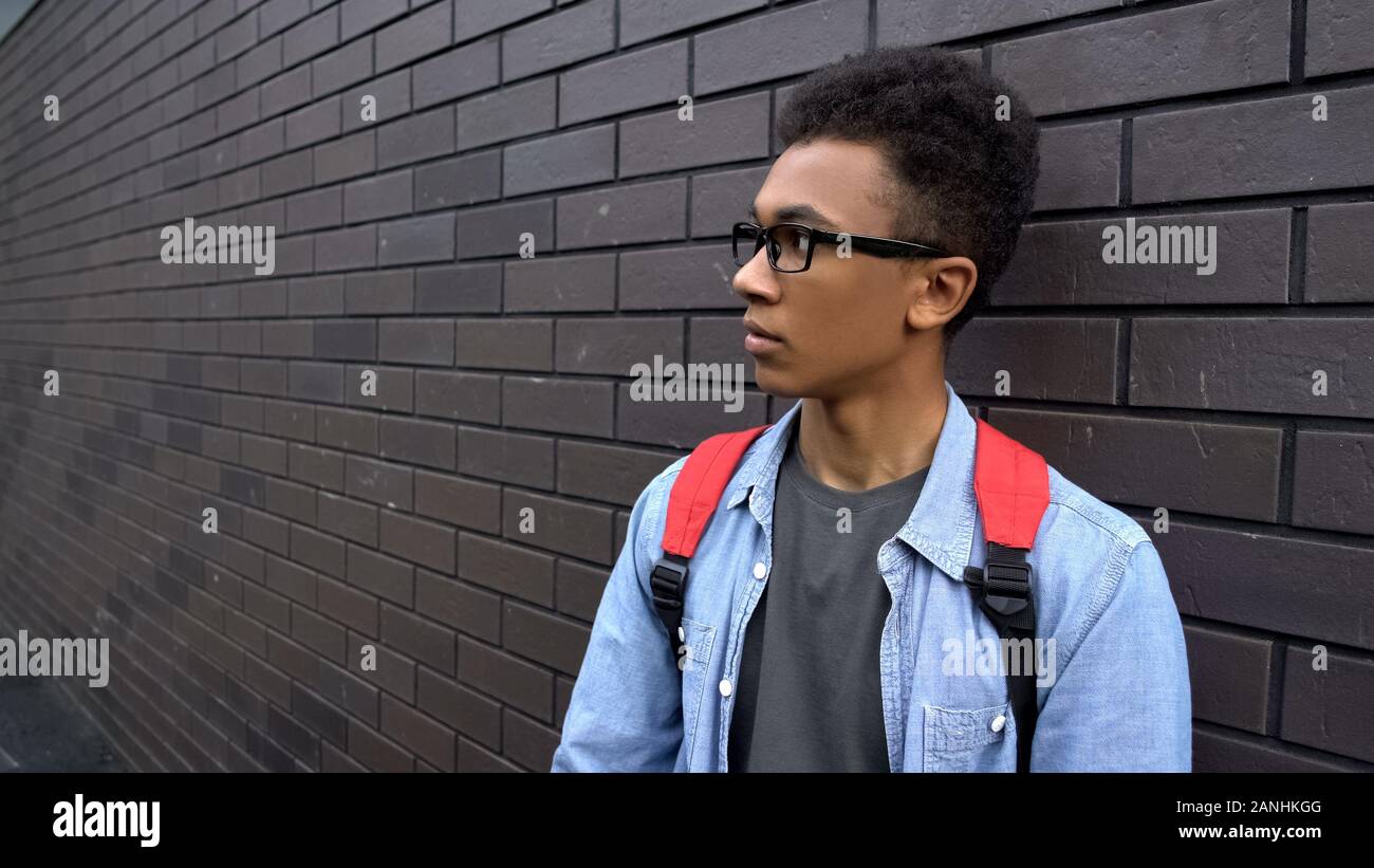 Scared black boy leaning against wall, intimidated victim of racial ...