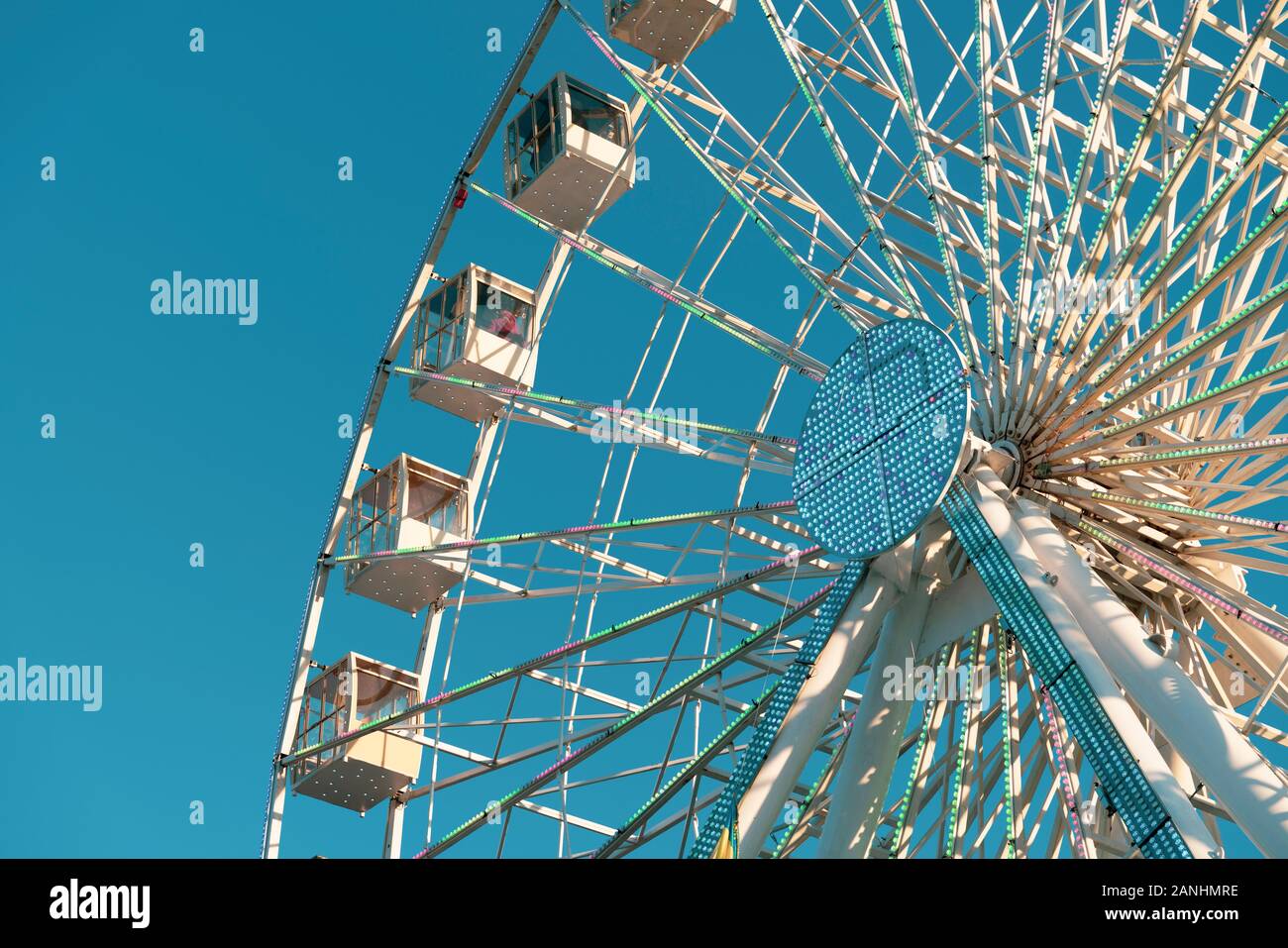 Large observation wheel is spinning on blue sky background. People are ...