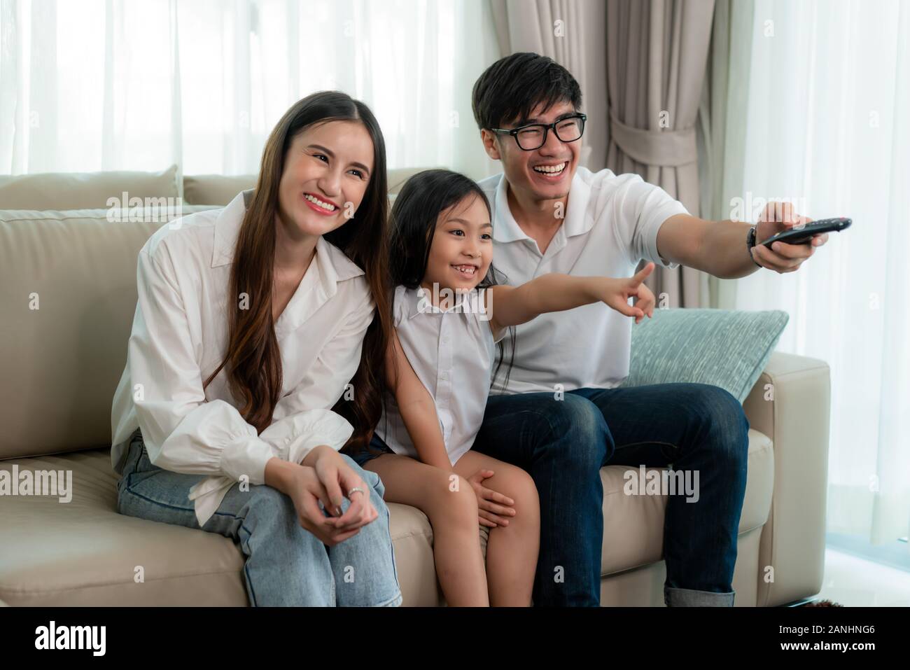 Candid of happy Asian family enjoy weekend activity by watching TV ...