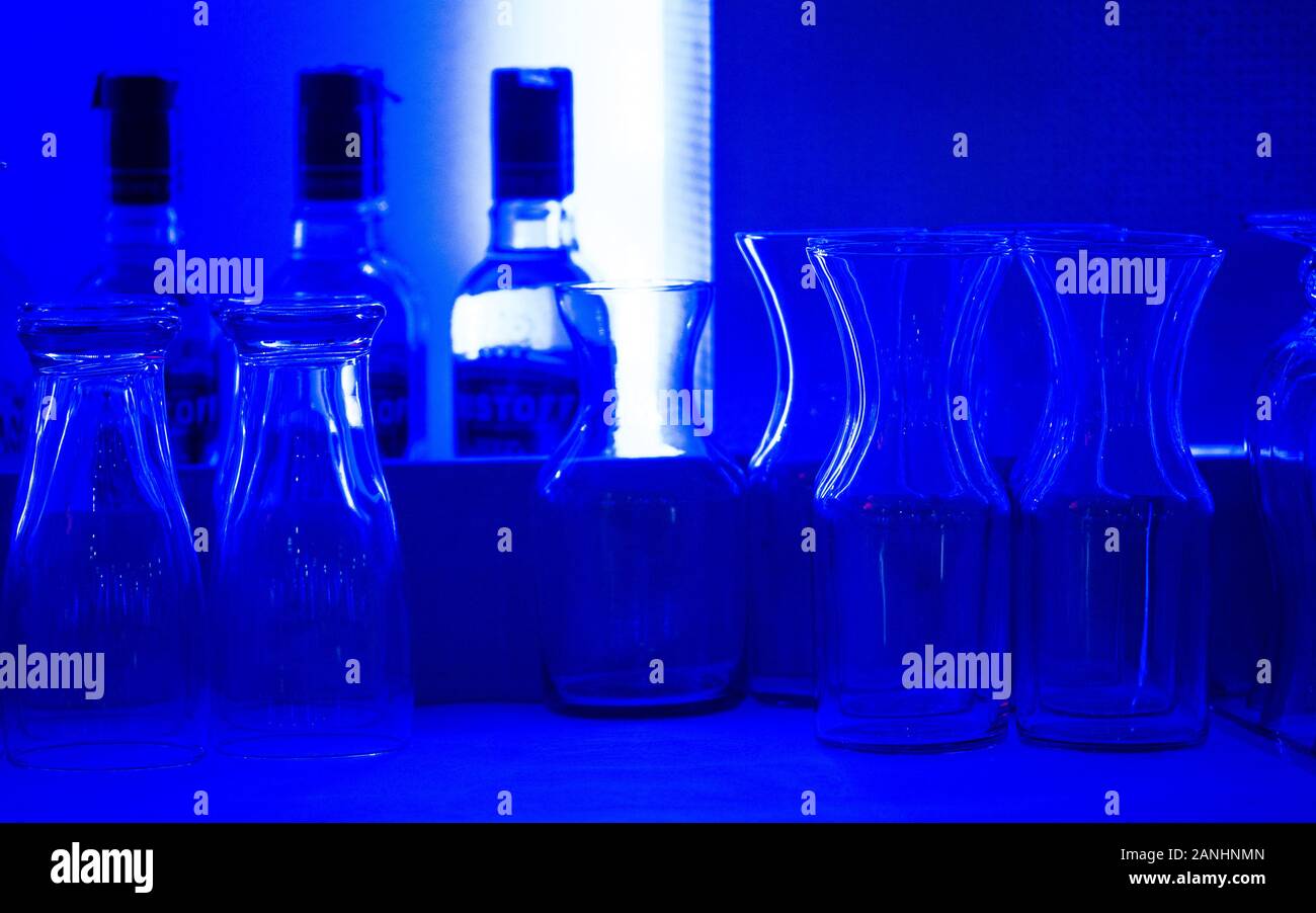 Blue Bar. Glasses lined up on the back of a contemporary bar under a ...