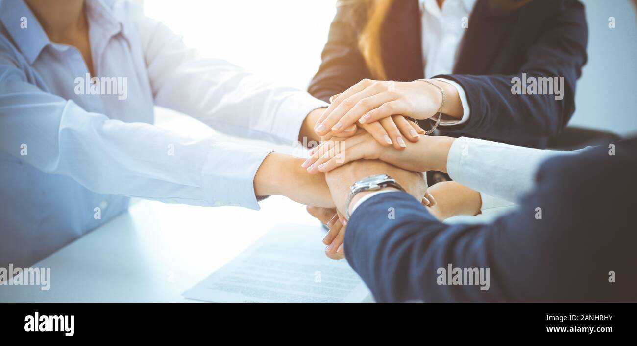 Business team showing unity with their hands together in sunny office ...