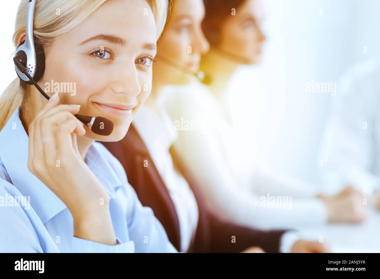 Group of diverse phone operators at work in sunny office. Handsome ...