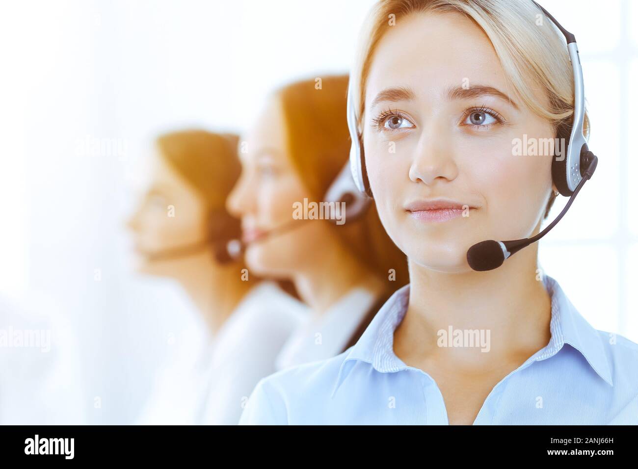 Group of diverse phone operators at work in sunny office. Handsome ...