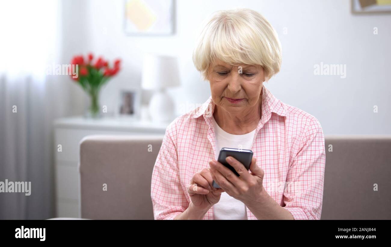 Serious elderly woman learning using new smartphone, technology for old ...