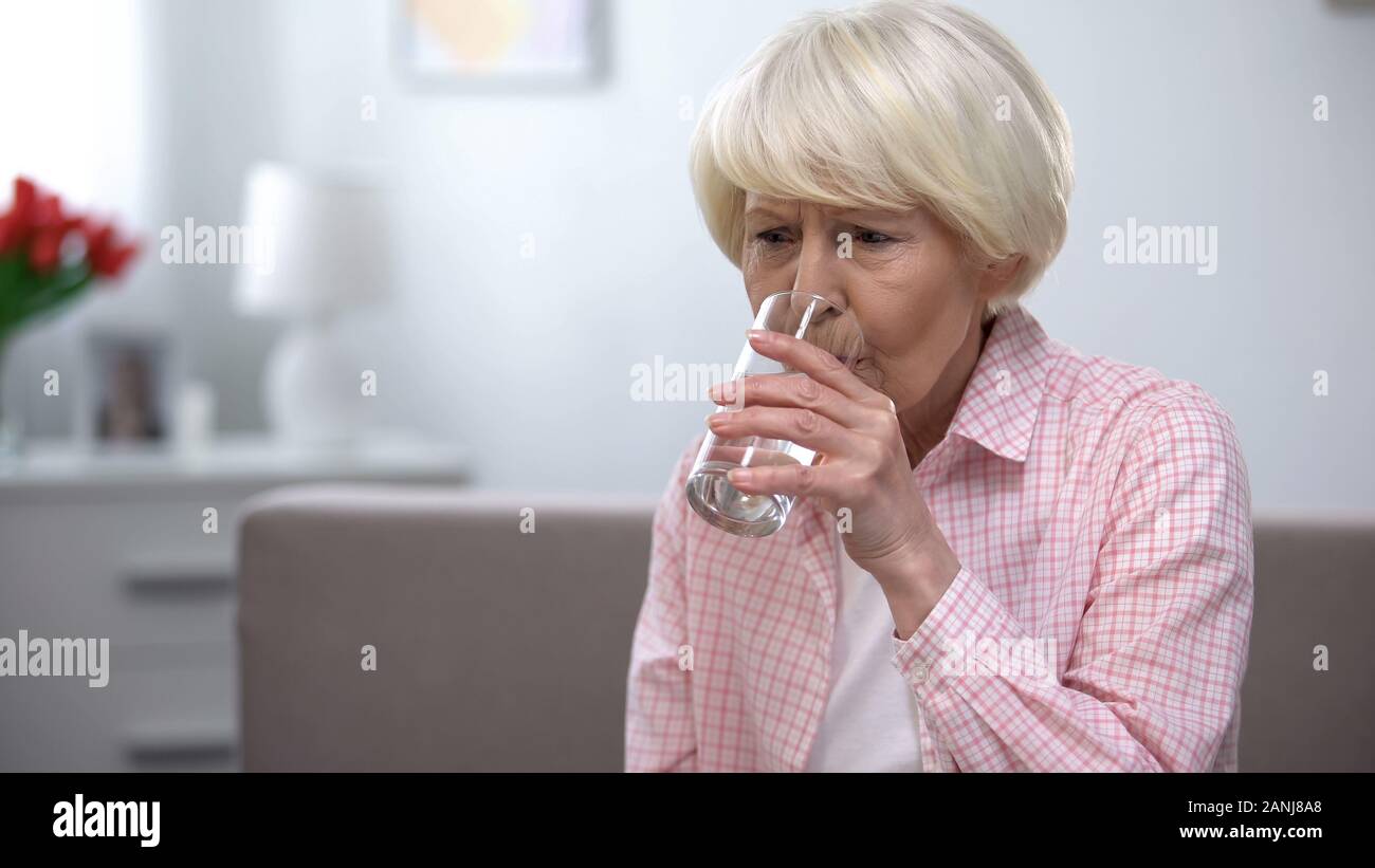 Upset senior woman feeling pain drinking water, health problems ...