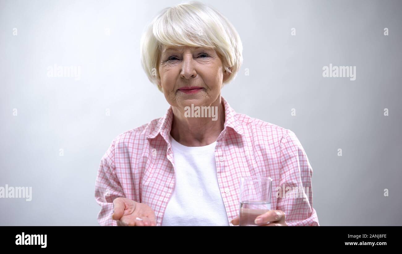 Old lady showing pills and glass of water at camera, pharmacology and ...