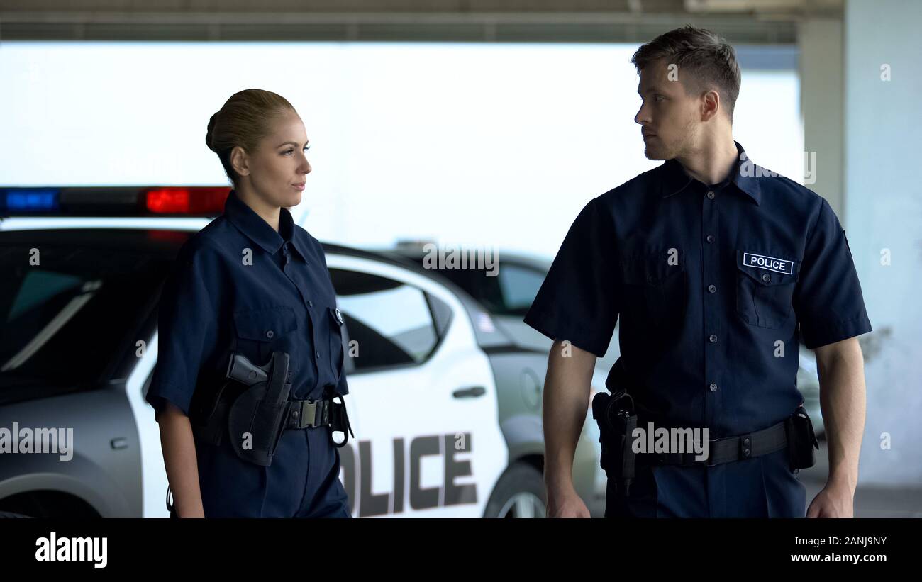 Two serious patrol officers standing near police car, starting work day ...