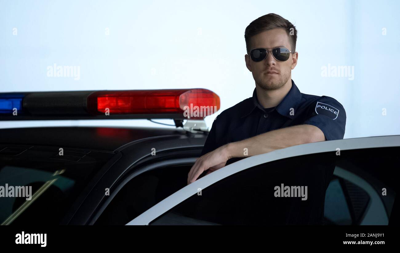 Professional police officer monitoring road standing near door of ...