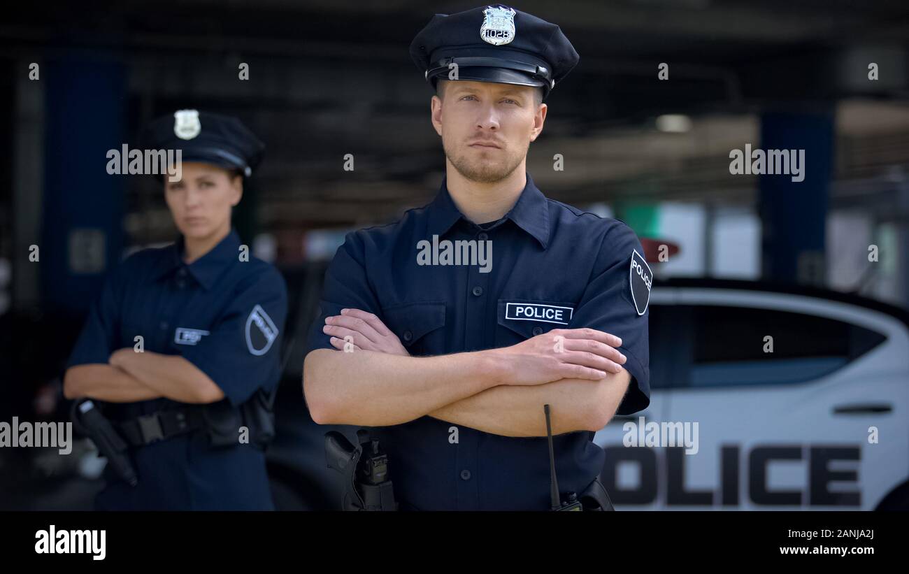 Confident male and female police officers in uniform standing near ...