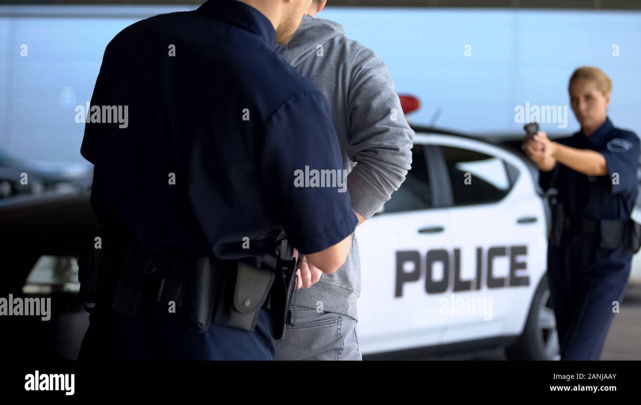 Police officers arresting dangerous criminal aiming gun, street crime ...