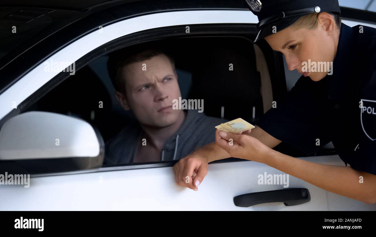Respectable police woman checking driver license of man in car, road ...
