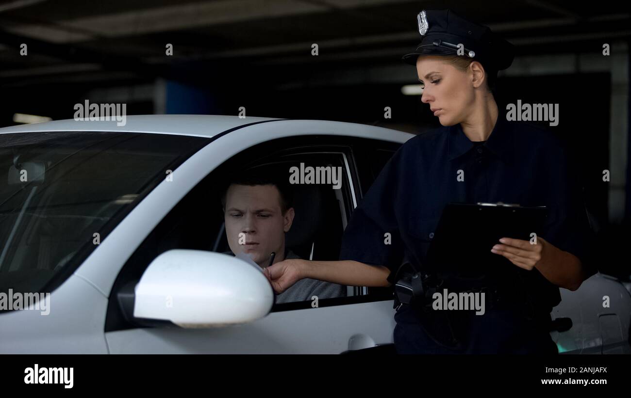 Female officer giving traffic ticket to male driver for parking ...