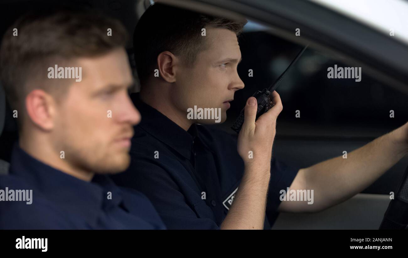 Policeman talking on portable radio in patrol car, calling in ...