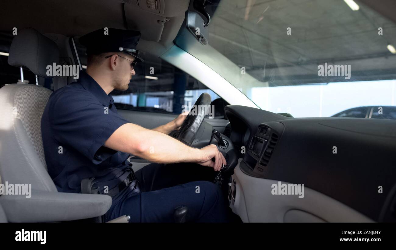 Confident policeman sitting in patrol car, turning ignition keys to ...