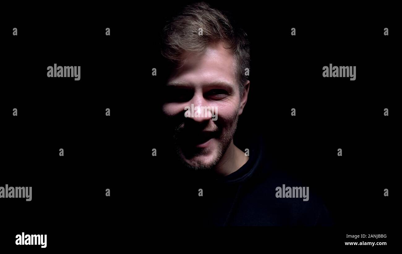 Crazy man laughing and staring into camera on black background, insane ...