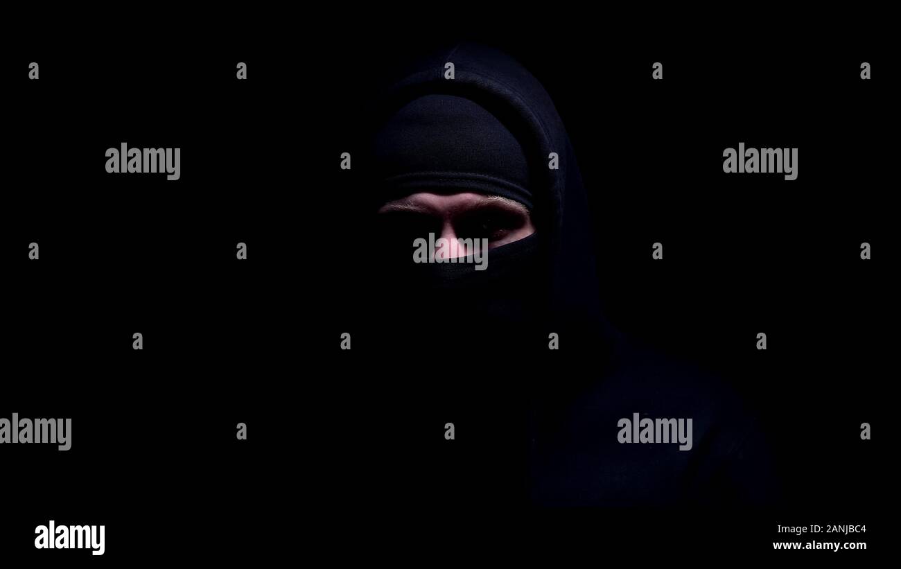 Spooky man in balaclava and hood looking into camera, member of ...