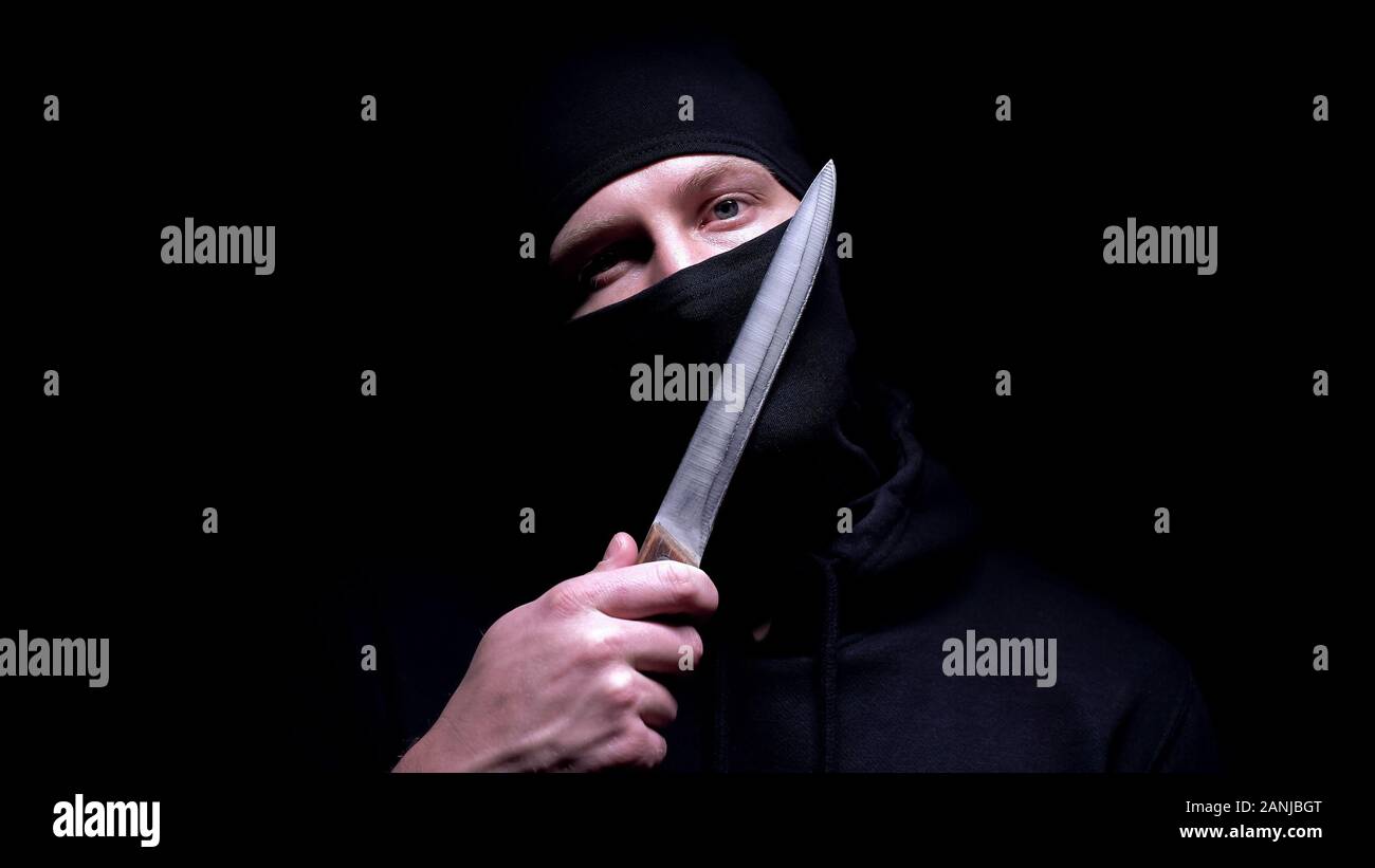 Insane murderer touching his masked face with big knife, threatening ...