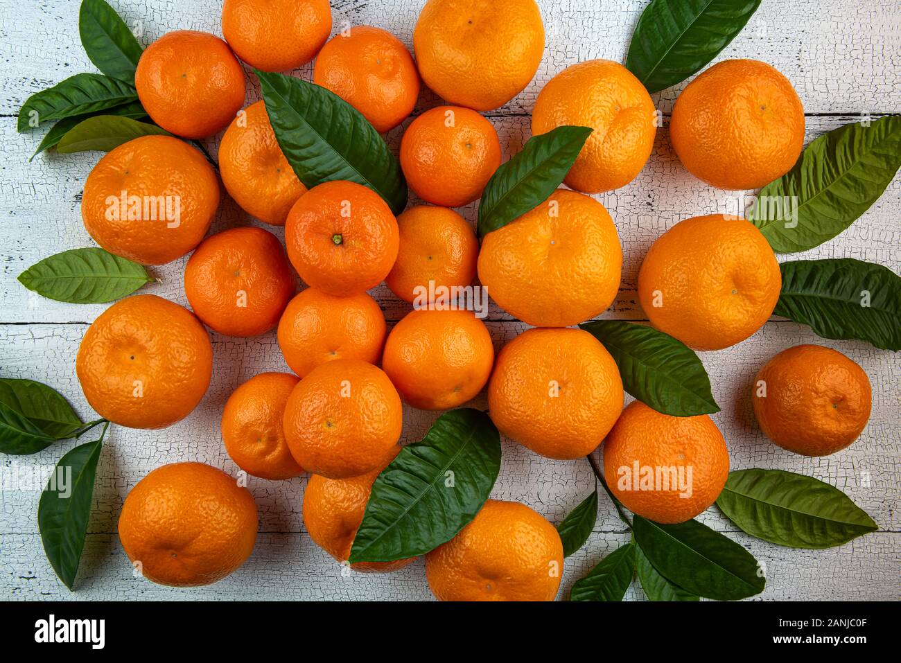 Group of whole bright orange tangerines with fresh green tangerine ...