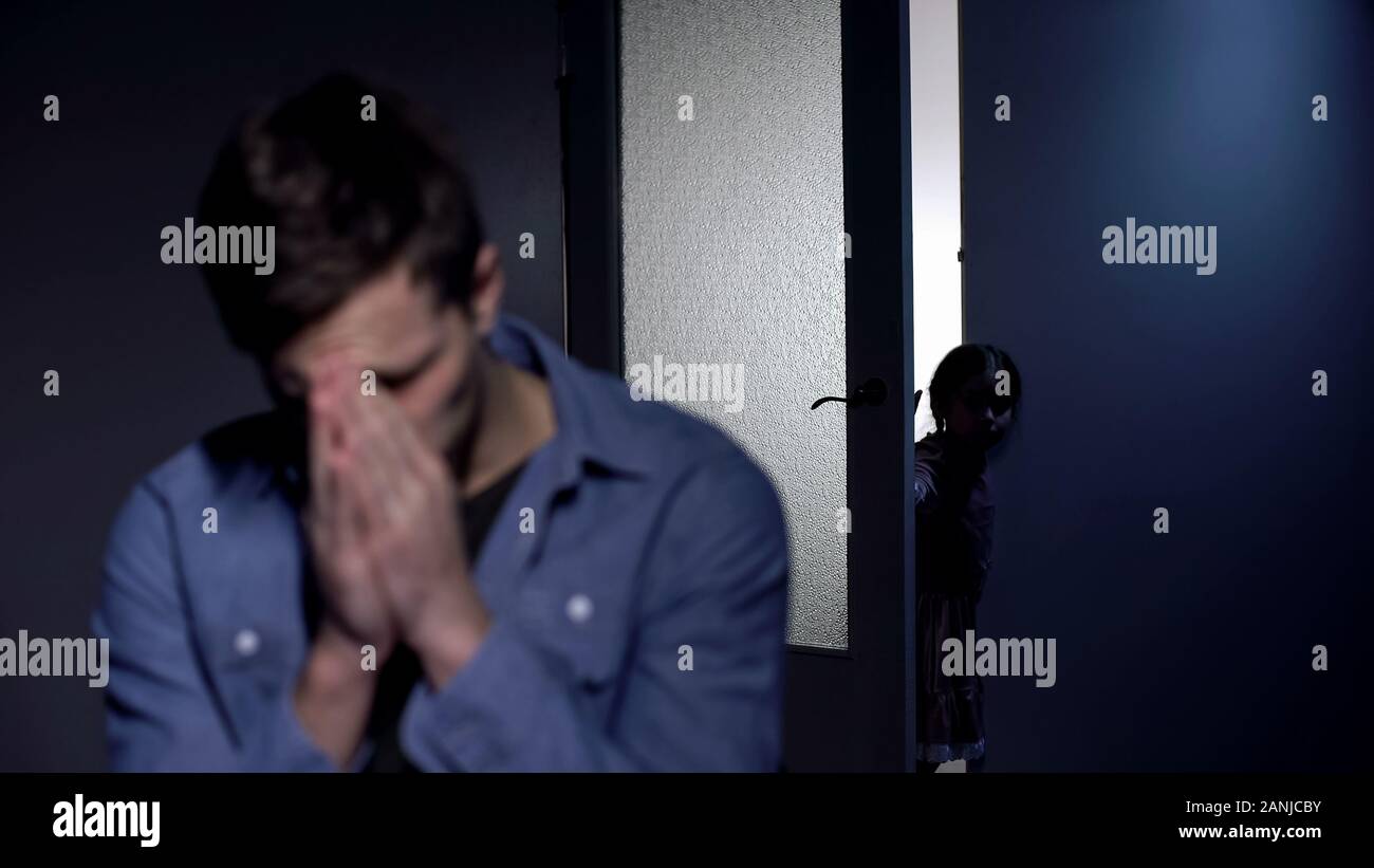 Depressed father crying in room, little daughter opening door, pain of ...