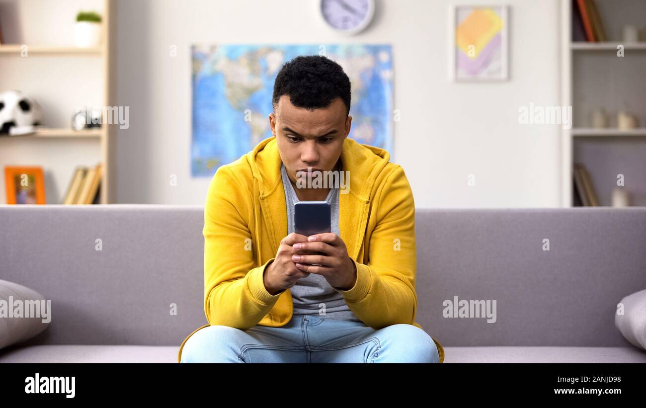 African-American teenager playing viral game on smartphone, gadget ...