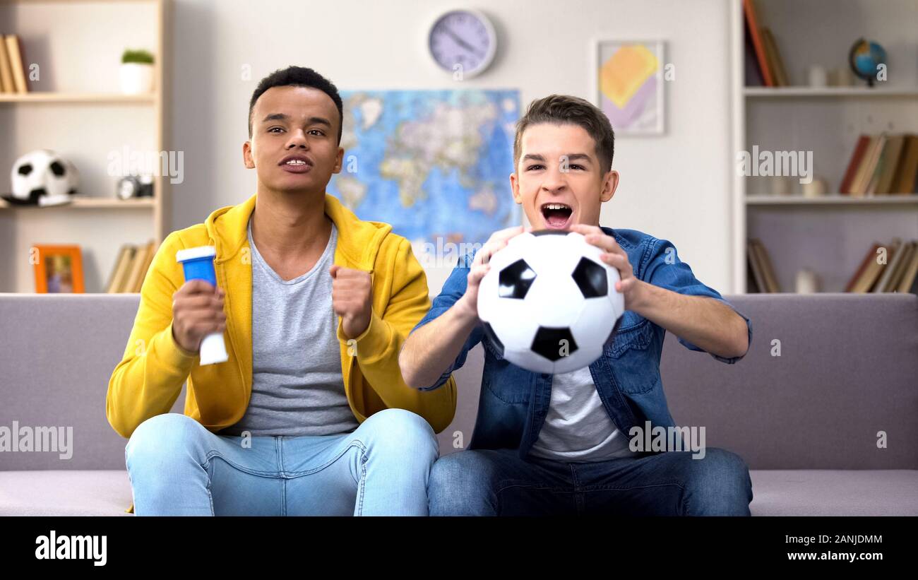 Teenage soccer fans with ball and horn cheering for football team at ...