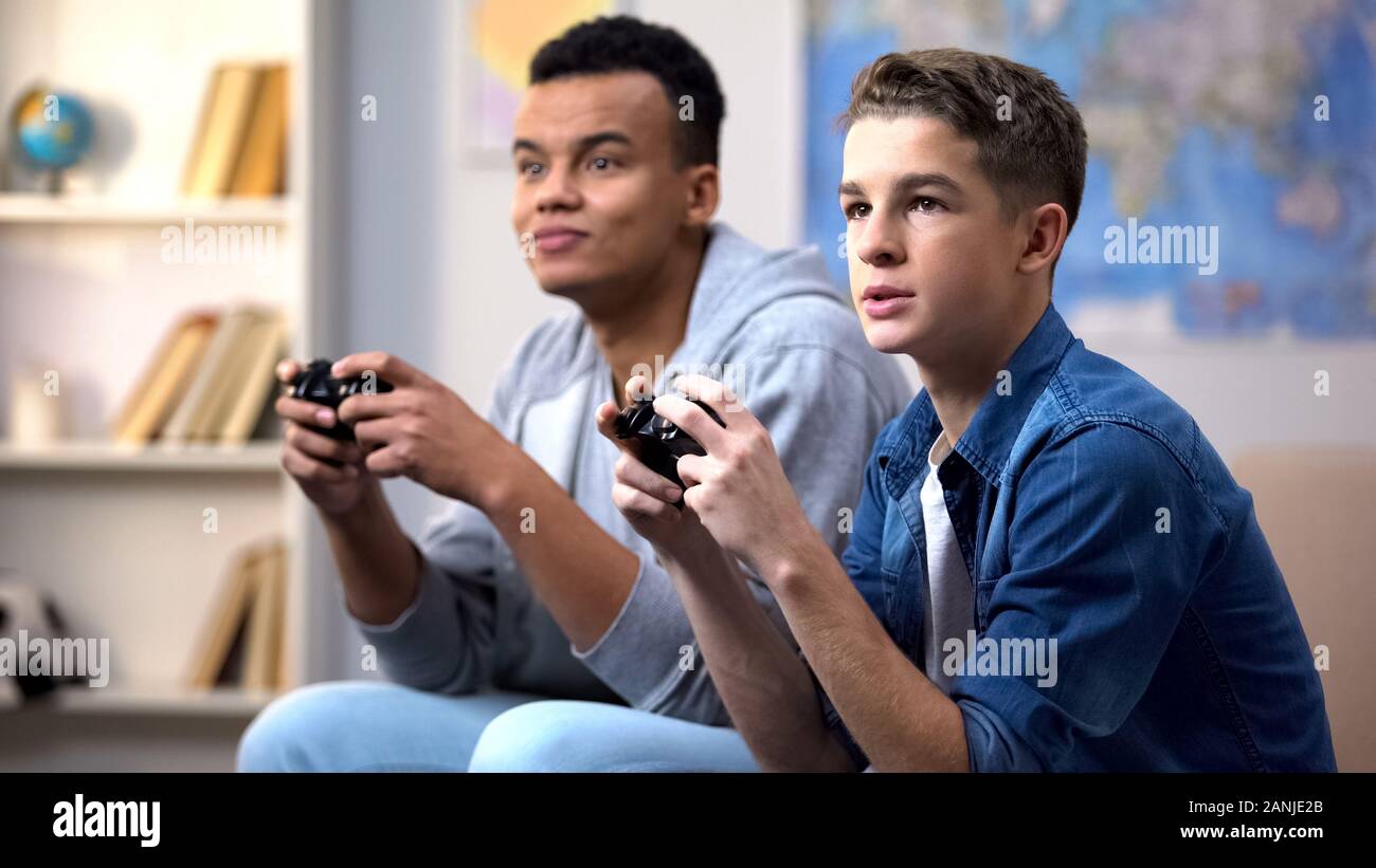 African-american and caucasian teenagers playing video games, gaming ...