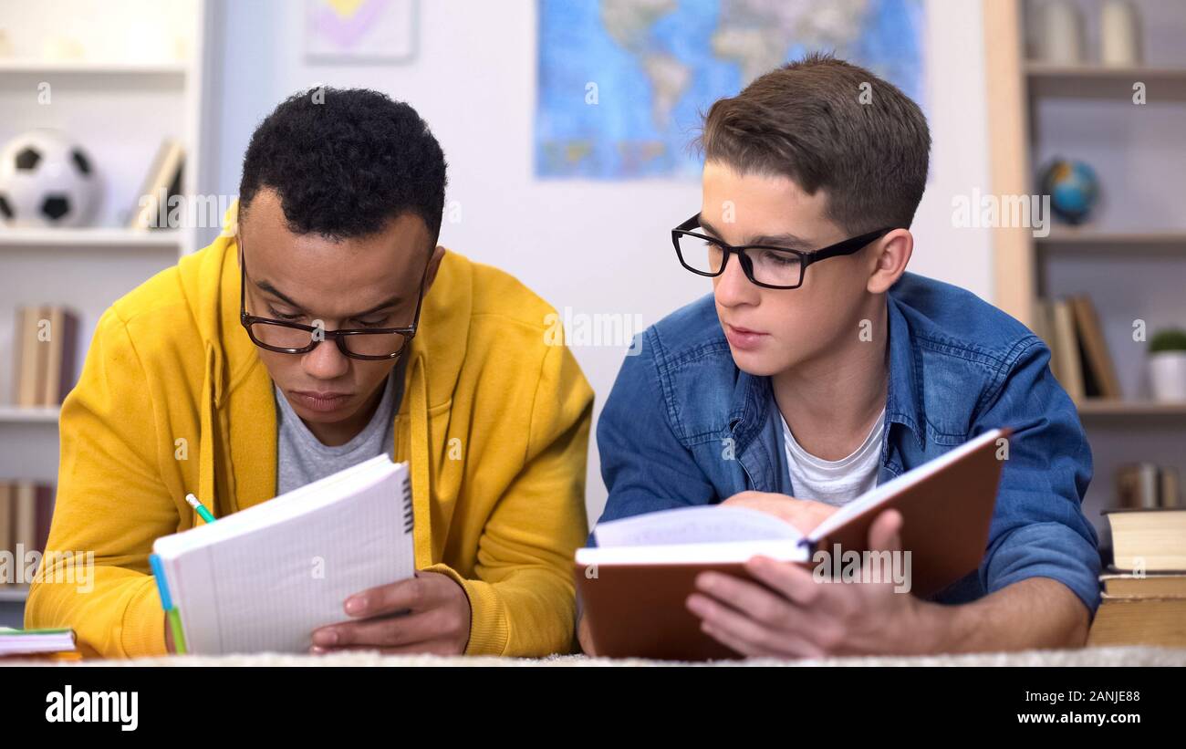 Black and caucasian college students writing report for lesson ...