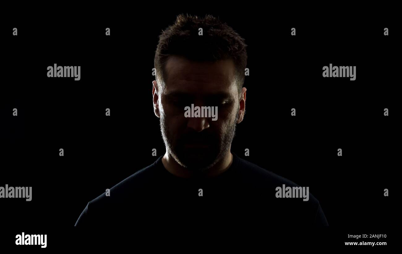 Sad male in shadow looking down feeling ashamed, problem frustration ...