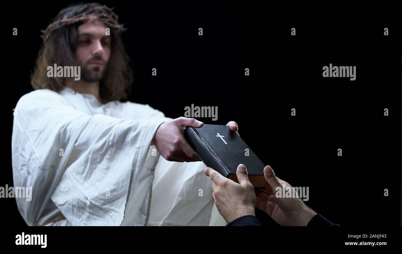 Messiah giving bible to man on dark background, holy scripture ...